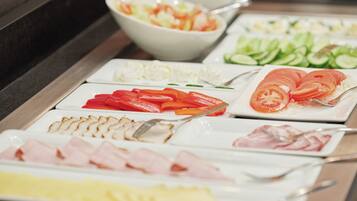 Buffet com diversas opções de comida, incluindo carnes fatiadas, legumes e saladas.