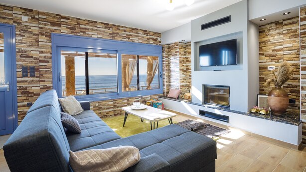 Uma sala de estar moderna com um sofá grande, uma TV fixada na parede e uma lareira.