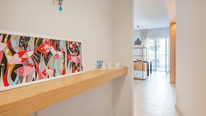 Um interior moderno com uma pintura abstrata colorida, uma placa de boas-vindas e vista para uma sala de jantar.