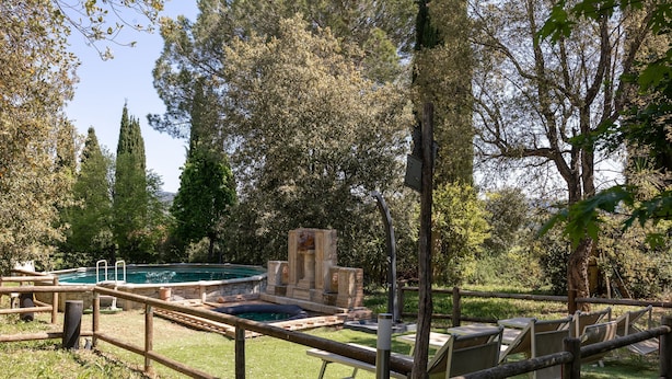 Uma área de piscina com hidromassagem, espreguiçadeiras e uma fonte de pedra.