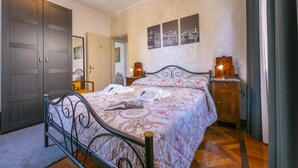 Quarto com cama, mesas de cabeceira, guarda-roupa e um quadro na parede.