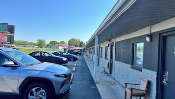 Um motel com uma fileira de quartos, uma área de estacionamento coberta e uma placa de fundo.