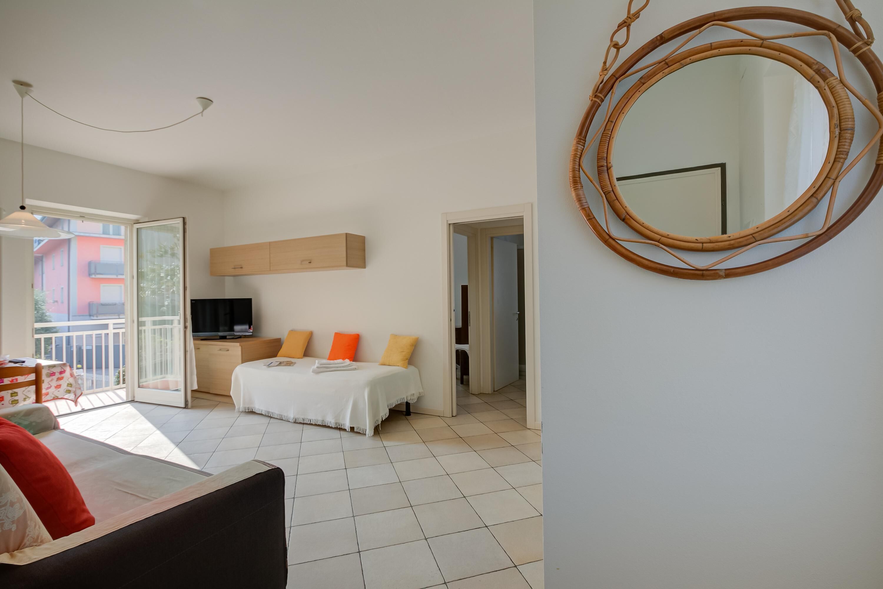 Quarto moderno com cama, televisão e varanda.