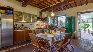 Uma cozinha com armários de madeira, uma mesa de jantar posta para quatro pessoas e uma geladeira verde.