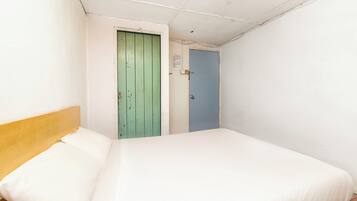 Quarto individual com cama de solteiro, cabeceira de madeira, uma porta verde e uma porta azul.