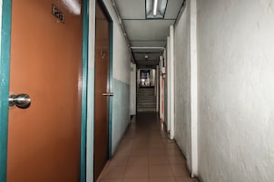 Um corredor comprido e estreito, com portas em ambos os lados, que leva a uma escadaria no final.