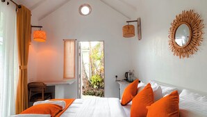 Quarto com uma cama grande, almofadas laranja, um espelho redondo e vista para o exterior.
