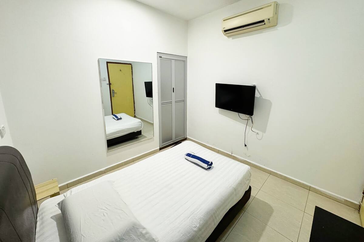 Quarto de hotel com cama, televisão, ar condicionado e guarda-roupa.