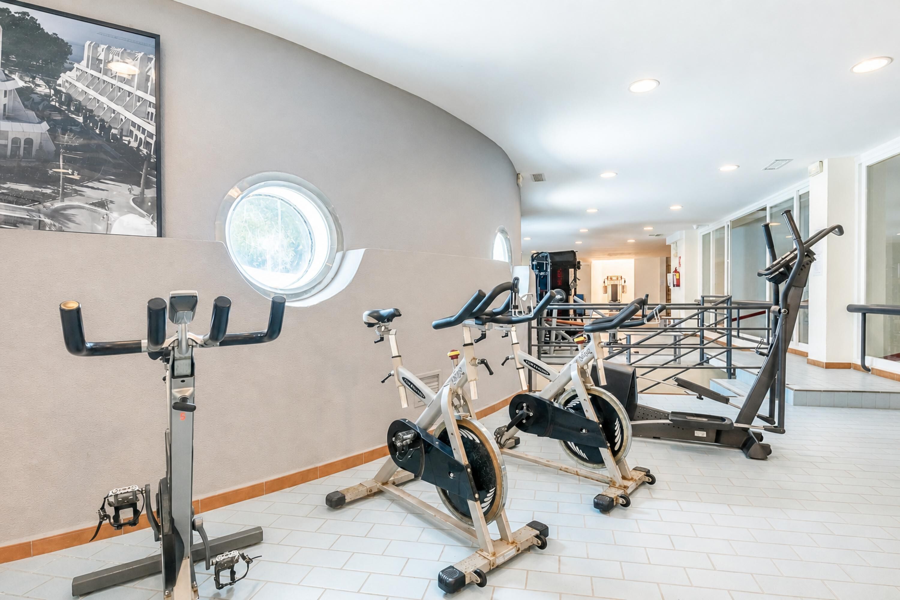 Uma academia com bicicletas ergométricas, esteira e máquina de pesos.