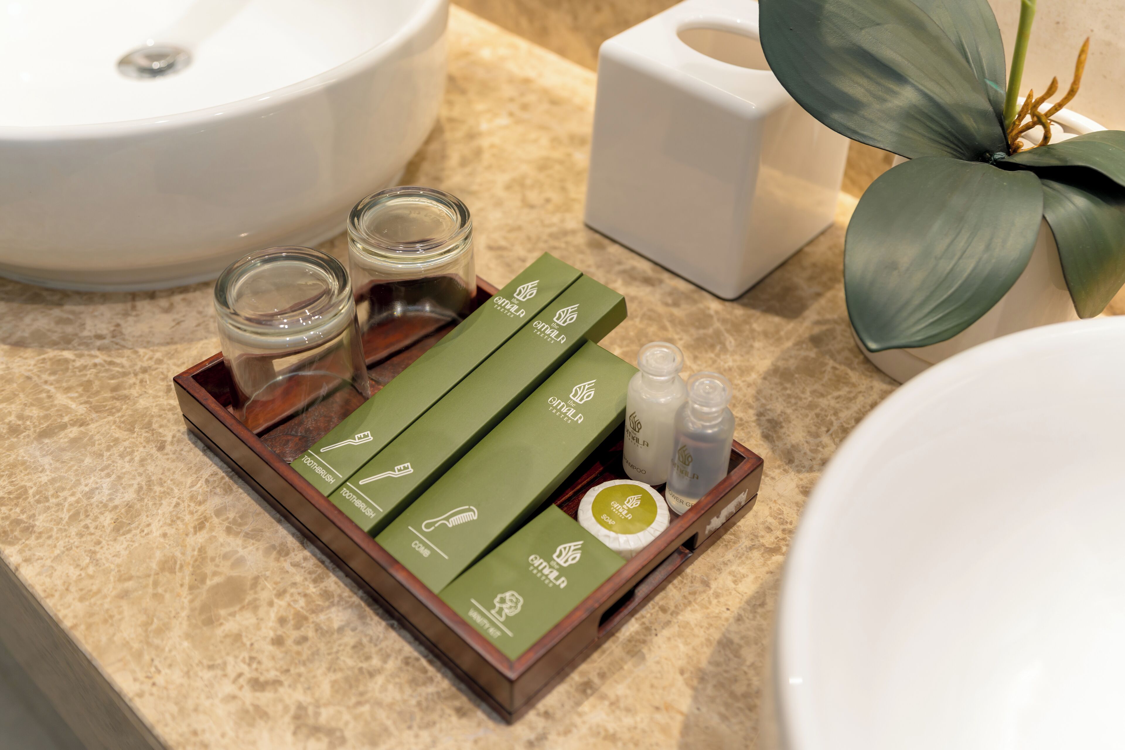 Casa de banho com lavatório, um suporte com produtos de higiene e uma planta em vaso.