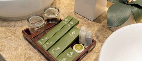 Casa de banho com lavatório, um suporte com produtos de higiene e uma planta em vaso.