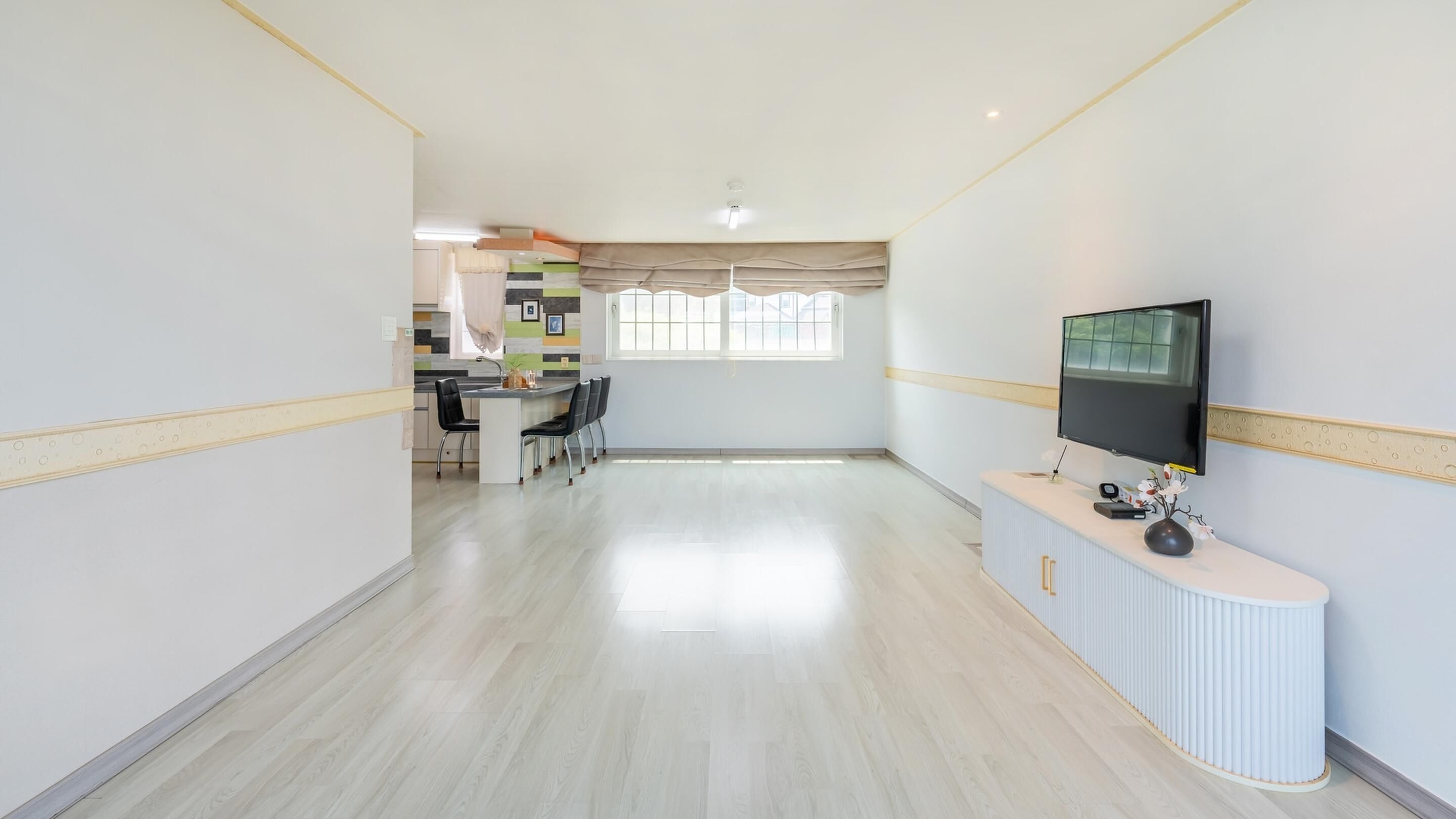 Quarto de hotel moderno com área de jantar, televisão e uma grande janela.