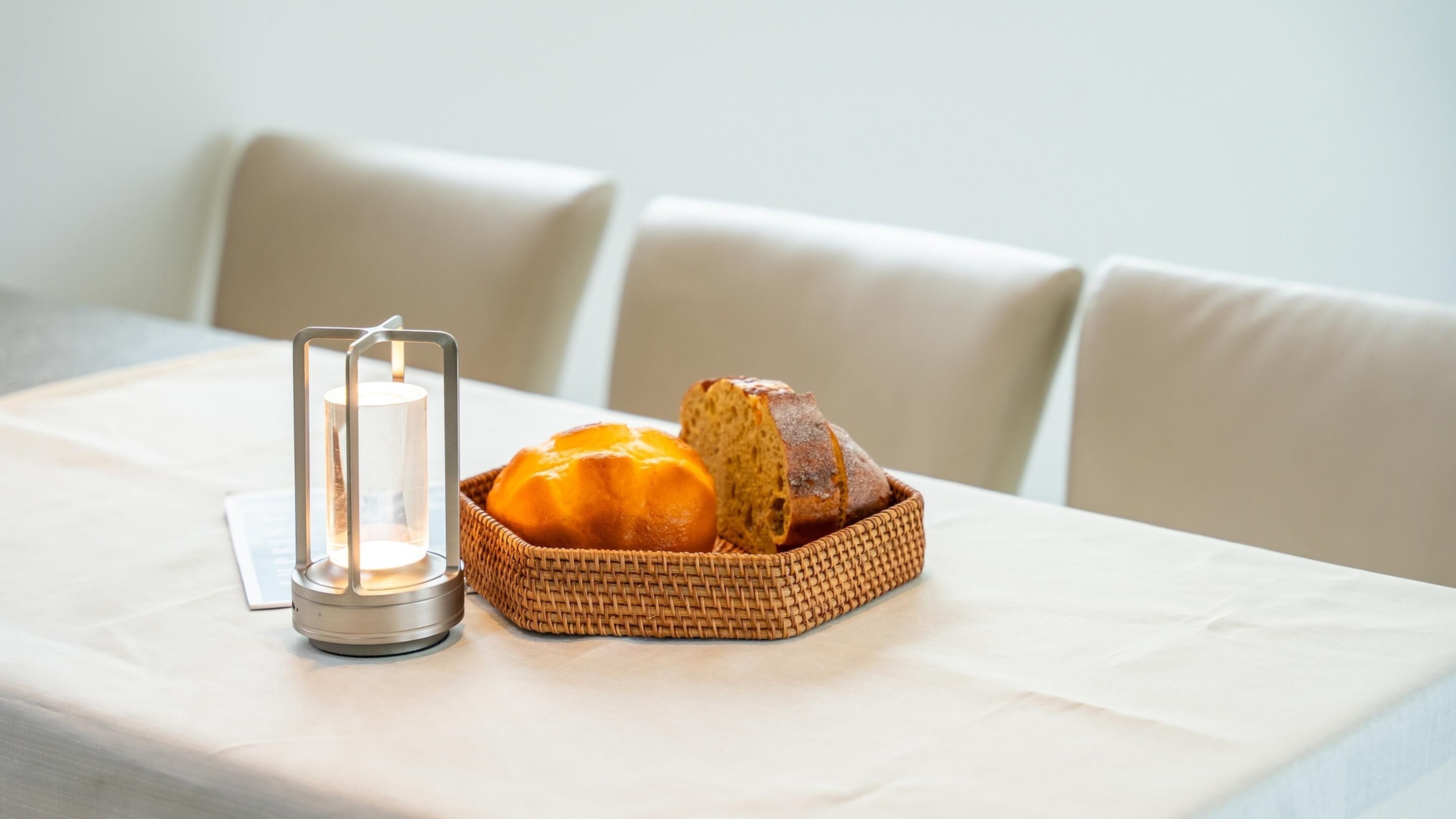 Uma mesa com uma vela, uma cesta de pão e um guardanapo.