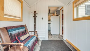 Um interior acolhedor com um banco de madeira, um cobertor estampado e vista para uma cozinha.
