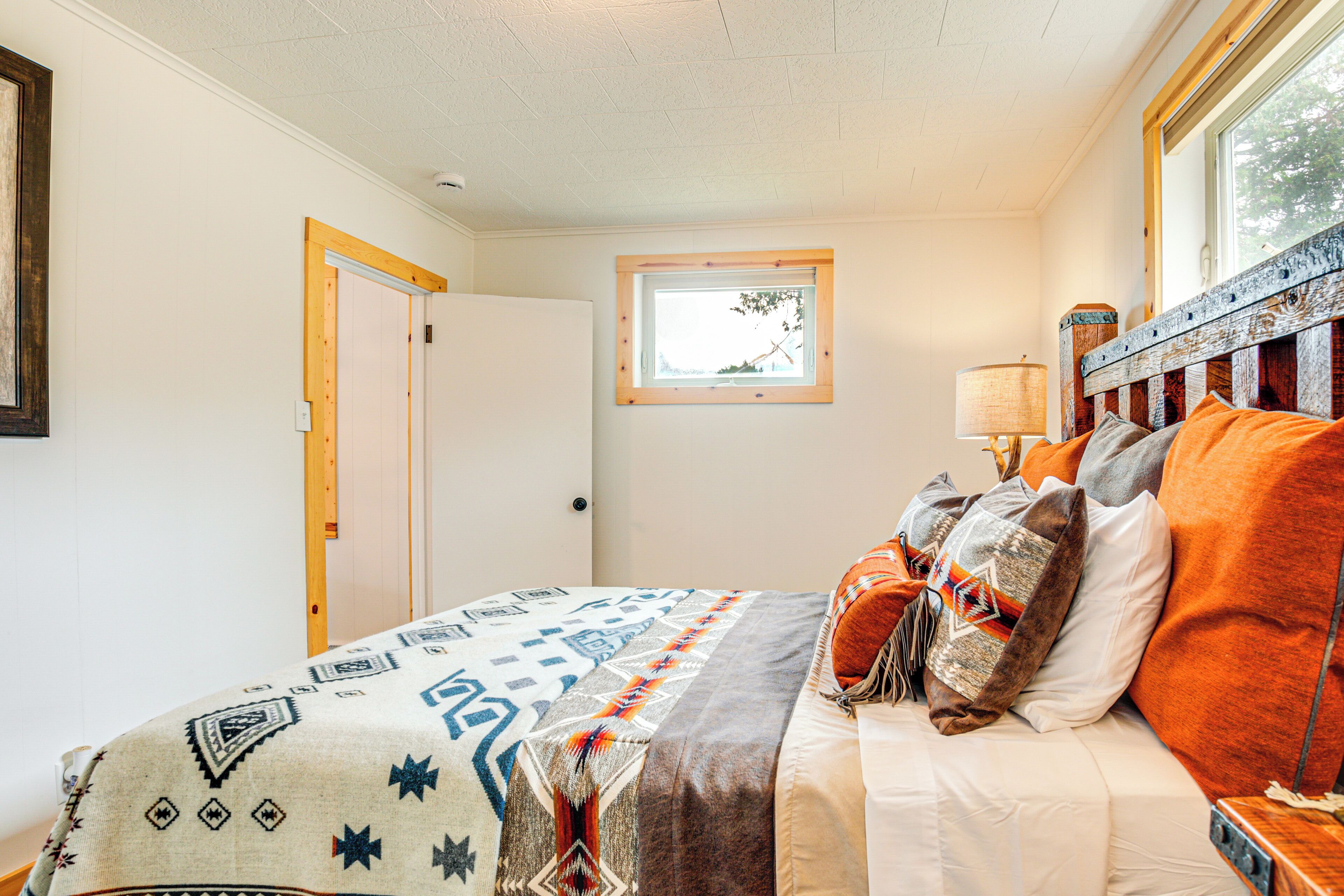 Quarto com cama, janela, porta e luminária fixada na parede.