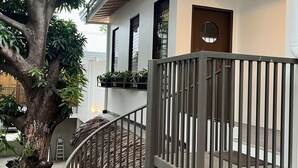 Escadaria com grades de metal que leva a um edifício branco com várias janelas e teto de madeira.