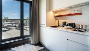 Cozinha moderna com uma janela grande, área de refeições com sofá e vista do céu.