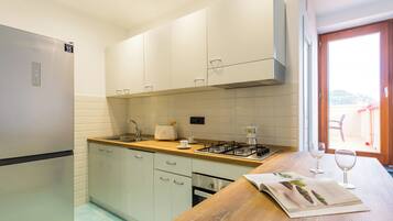 Apartamento, vista para o mar | Cozinha privada | Um frigorífico/congelador grande, um forno, uma máquina de lavar louça