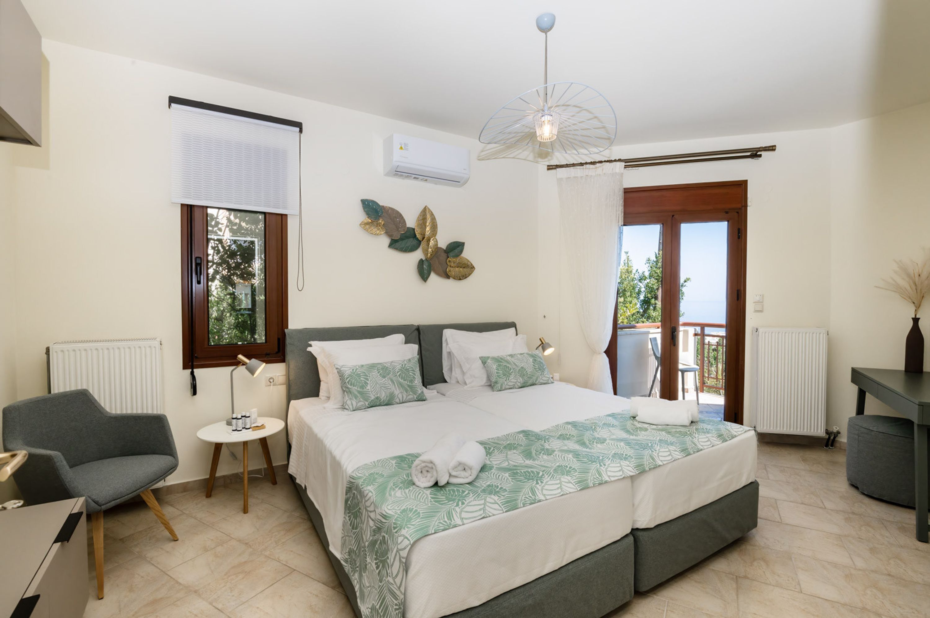 Quarto com cama, cadeira, mesa pequena e varanda.
