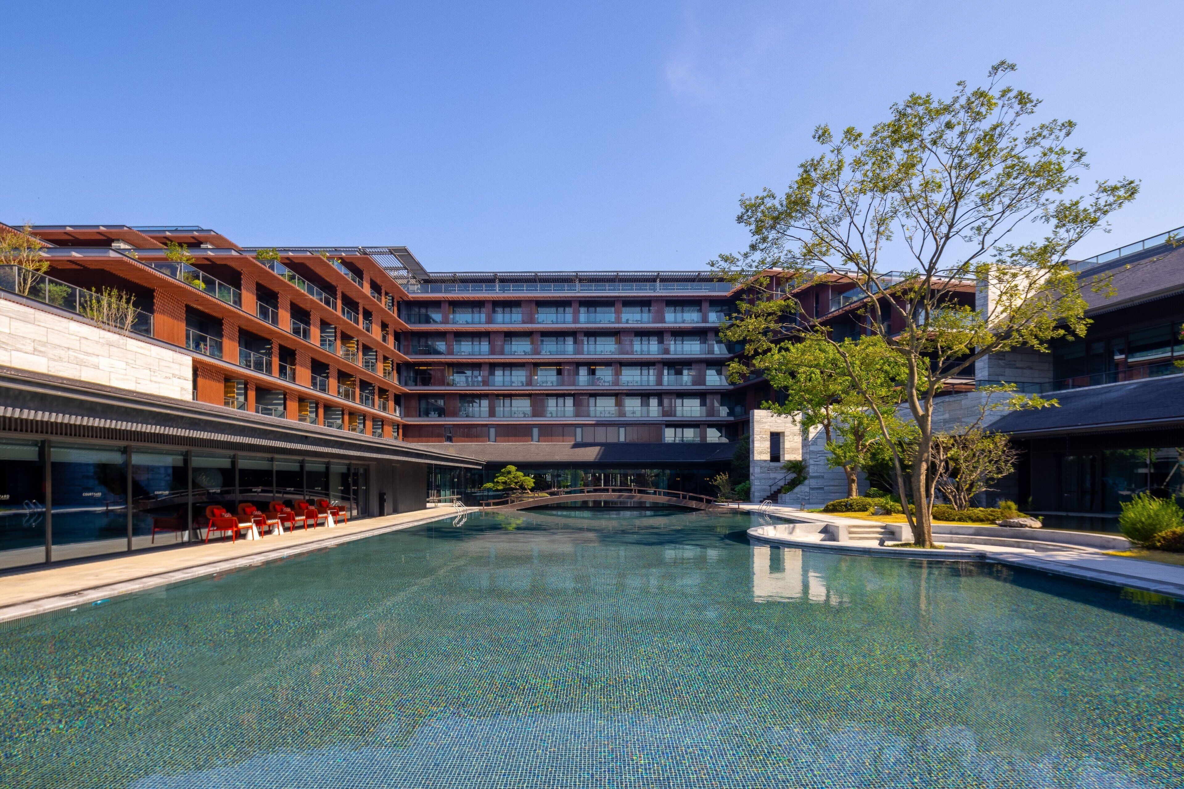 Um hotel moderno com piscina, vários andares e arquitetura que combina vidro e tijolo.