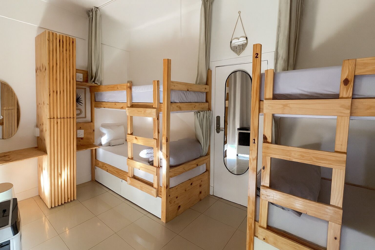 Quarto com beliches, guarda-roupa de madeira, espelho e porta com número.