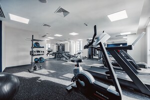 Academia moderna com esteiras, aparelhos de musculação e bolas de exercício.