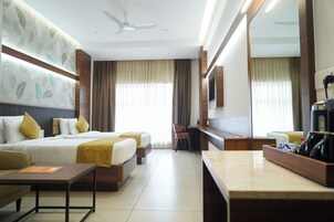 Quarto de hotel com cama, escrivaninha, cadeira, máquina de café e televisão.