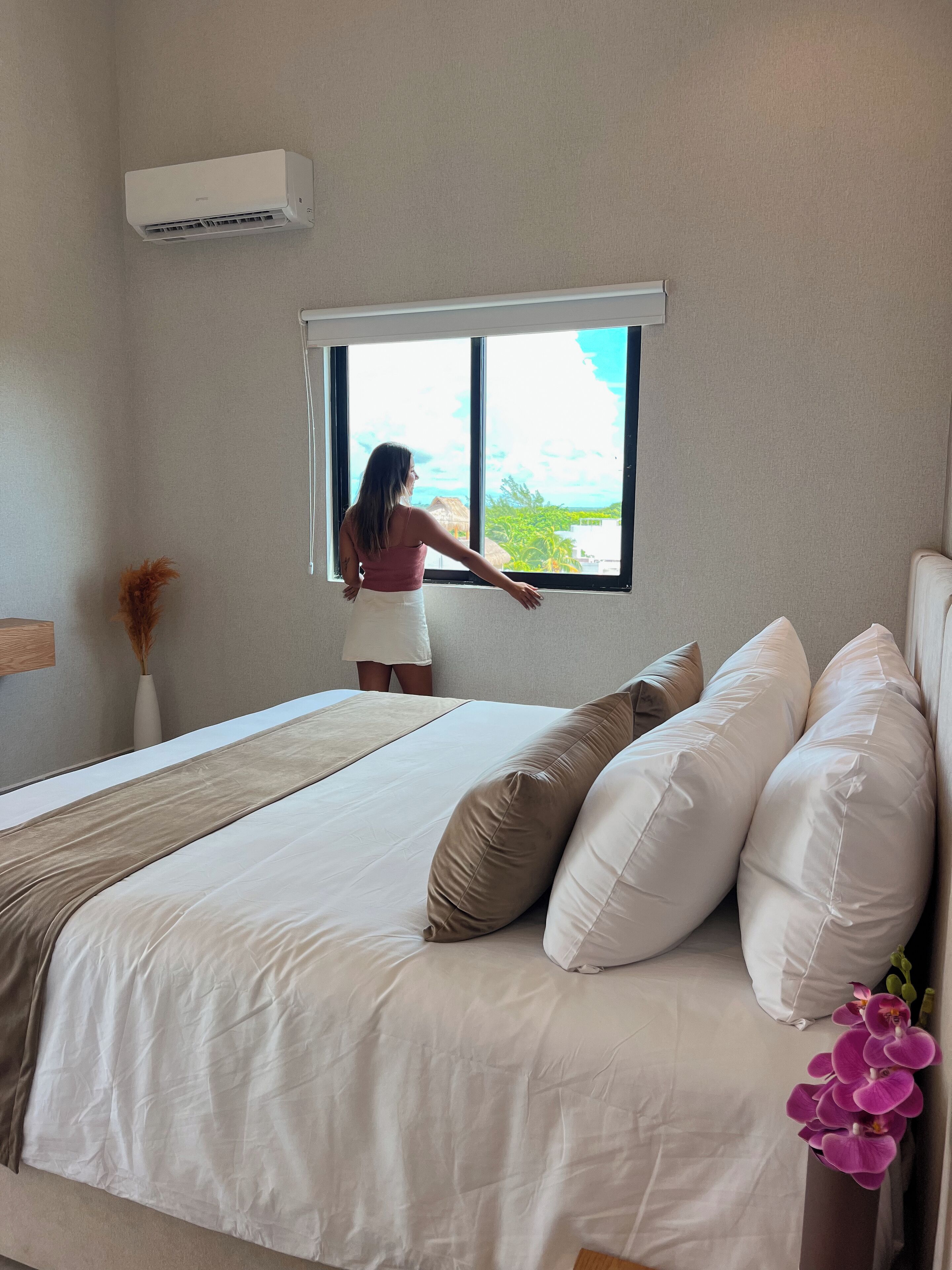 Quarto com cama, janela e ar condicionado fixado na parede.