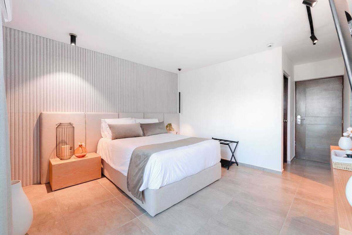 Um quarto moderno com uma cama grande, mesas de cabeceira e um criado-mudo.