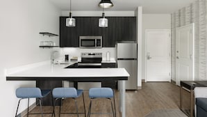 Uma cozinha moderna com uma ilha central, banquetas, micro-ondas, forno e frigorífico.