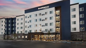 Um hotel de vários andares com design moderno, apresentando uma entrada imponente com fachada de vidro e uma placa com a inscrição "Residence Inn by Marriott".