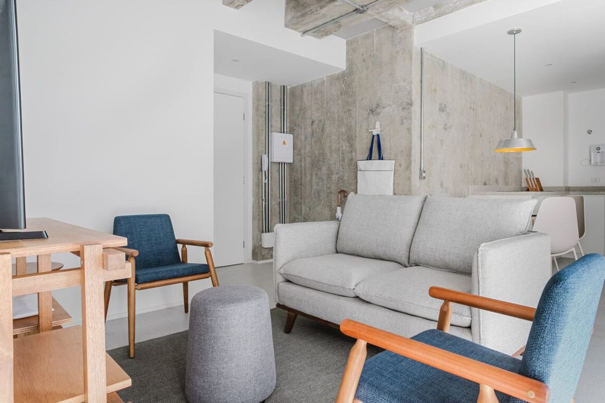 Uma sala de estar moderna com um sofá, cadeiras, uma mesa de centro e uma televisão.