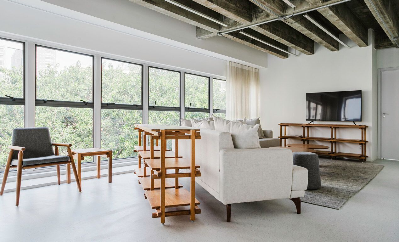Uma sala de estar moderna com sofá, cadeiras, televisão e mesa de madeira.