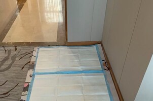 Um quarto com piso ladrilhado, tapete estampado e um colchão branco no chão.