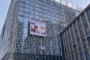 Um edifício com fachada em forma de grade, um grande outdoor e uma placa com caracteres chineses.