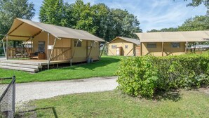 Um camping com duas tendas, cada uma com varanda e área de estar.