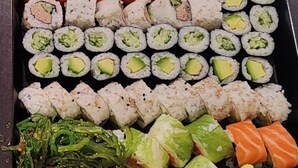 Uma bandeja com diversos tipos de sushi e legumes.