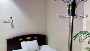 Quarto de hotel com cama bem arrumada, mesa de cabeceira com abajur e tomada na parede.