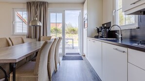Cozinha moderna com  área de refeições, janelas amplas e vista para o exterior.