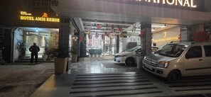 Entrada de hotel com uma faixa de pedestres e uma carrinha branca estacionada à direita.