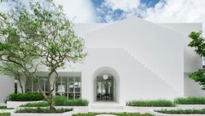 Um edifício moderno com fachada branca, uma entrada em arco central e uma escadaria.