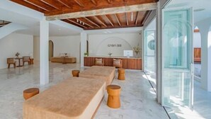 Um hall de hotel moderno com teto de madeira, balcão de recepção e área de estar com pufes.
