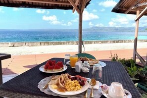 Mesa com itens de café da manhã e vista para a praia.
