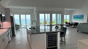 Uma cozinha moderna com uma ilha grande, eletrodomésticos embutidos e vista para o oceano.