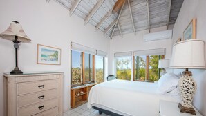Quarto com cama, cômoda, duas janelas e ventilador de teto.
