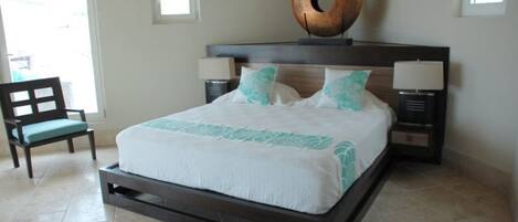 Quarto com uma cama, duas mesas de cabeceira, uma cadeira e um objeto decorativo grande na cabeceira.