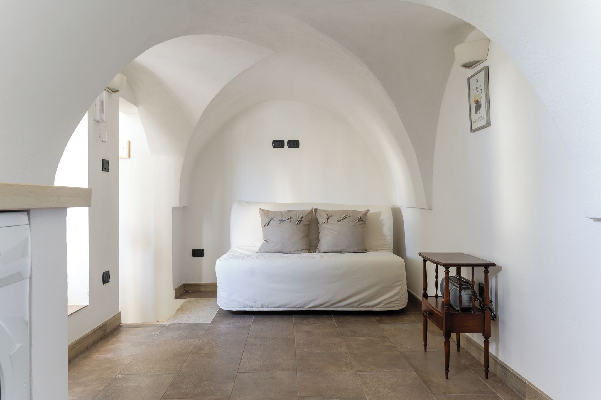 Quarto com cama, mesa de cabeceira e teto curvo.