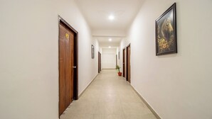 Um corredor com portas de madeira, um vaso com planta e quadros nas paredes.