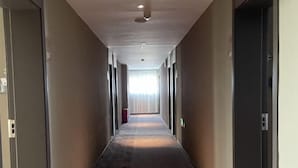 Um corredor longo e estreito com portas de ambos os lados, que dá acesso a quartos.
