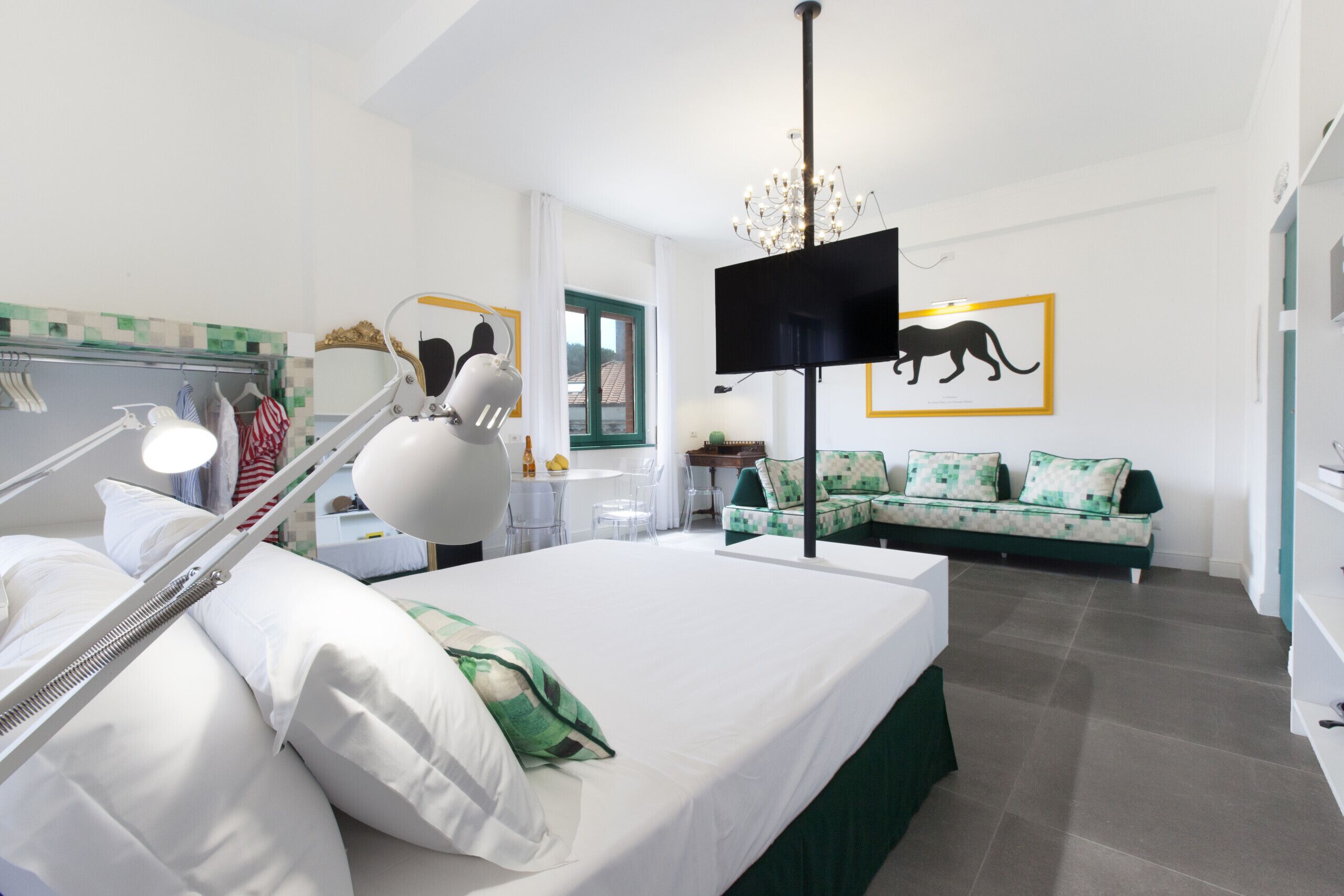 Quarto de hotel moderno com uma cama, uma escrivaninha, uma cadeira, uma televisão e um sofá.